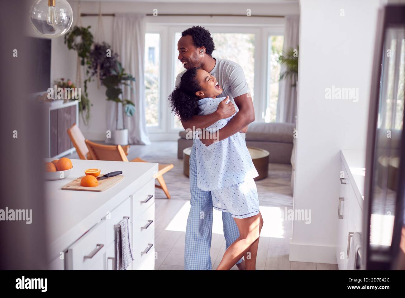 Loving Couple Wearing Pyjamas Hugging In Kitchen At Home Together Stock ...