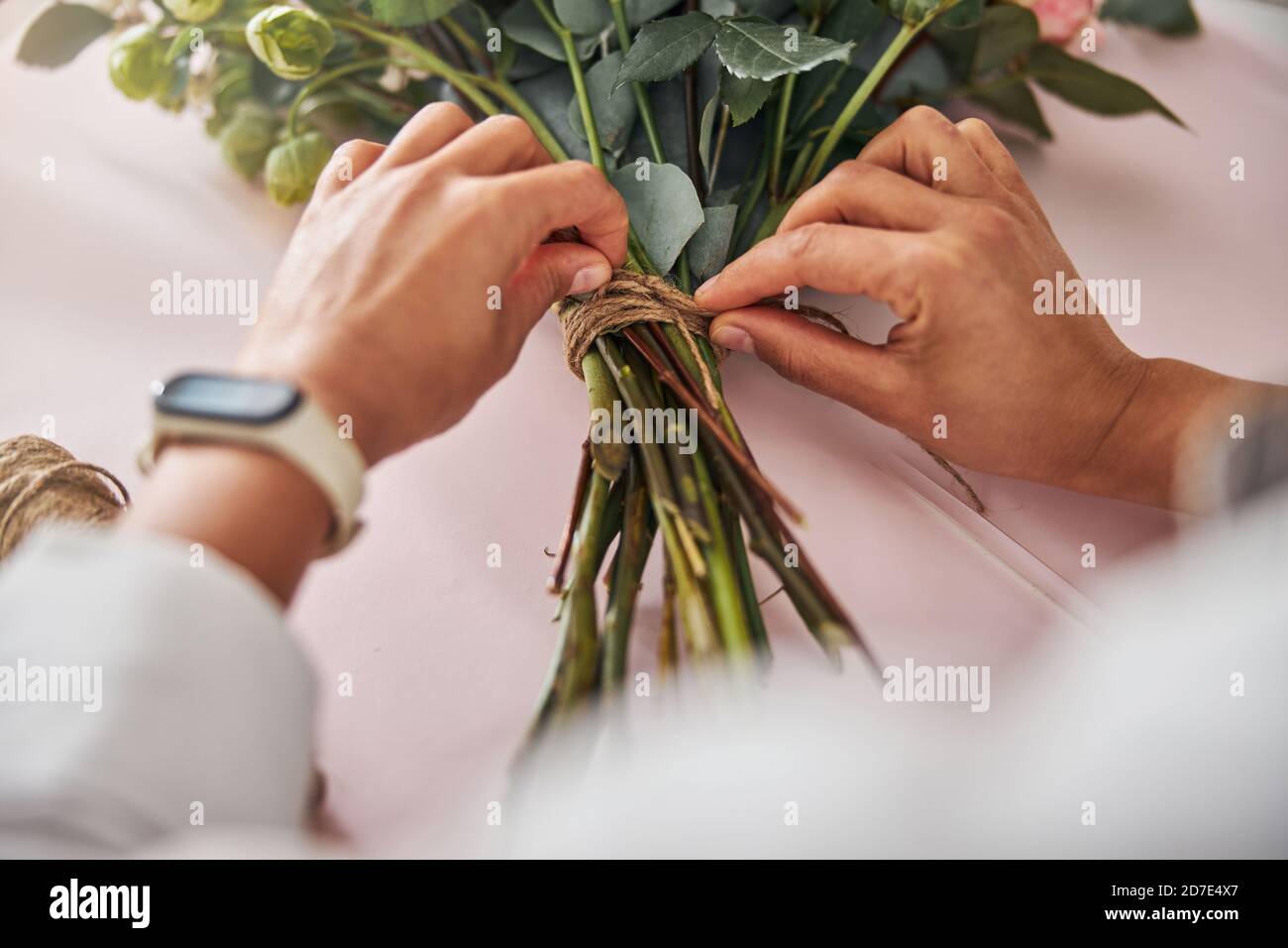 Qualified florist tying a brown thread around a bunch of flowers Stock ...