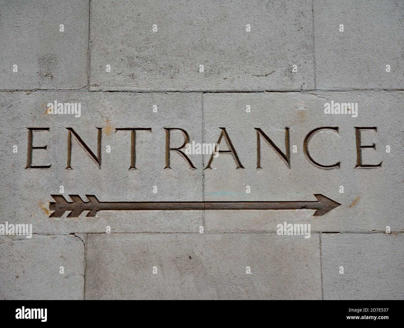 Entrance sign with arrow carved into an historic stone building Stock ...