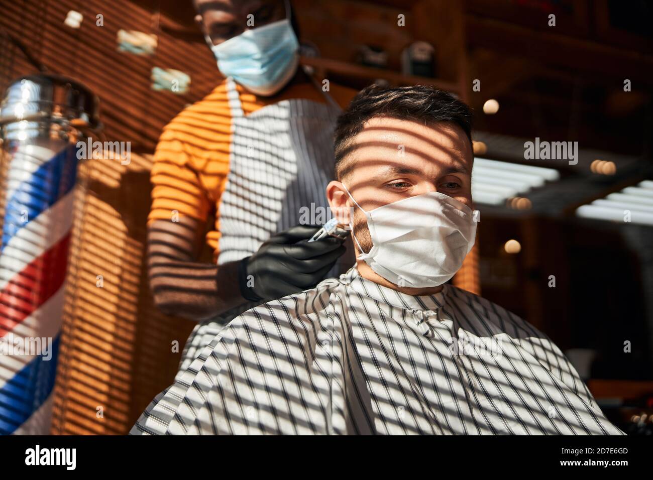 Handsome man in medical mask getting haircut in barbershop Stock Photo ...