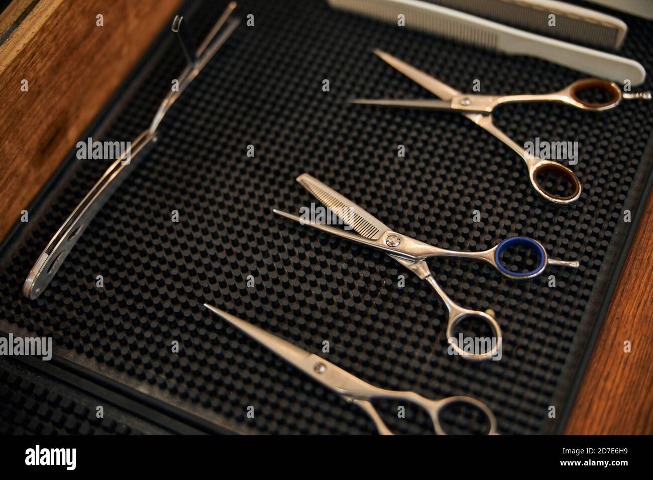 Professional barber scissors and straight razor on black rubber mat ...