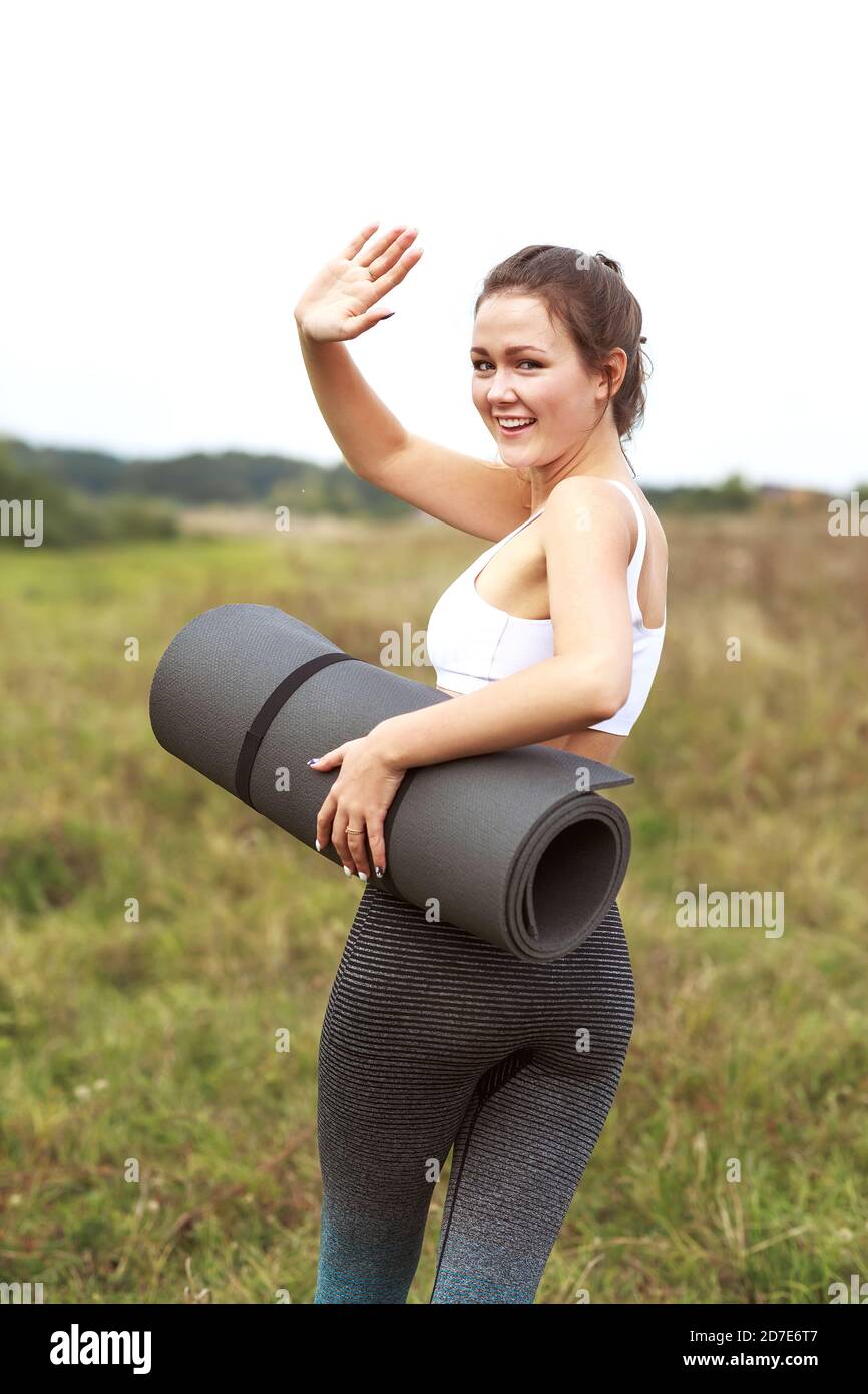 A young athletic girl is going to do yoga exercises outside on a sports ...