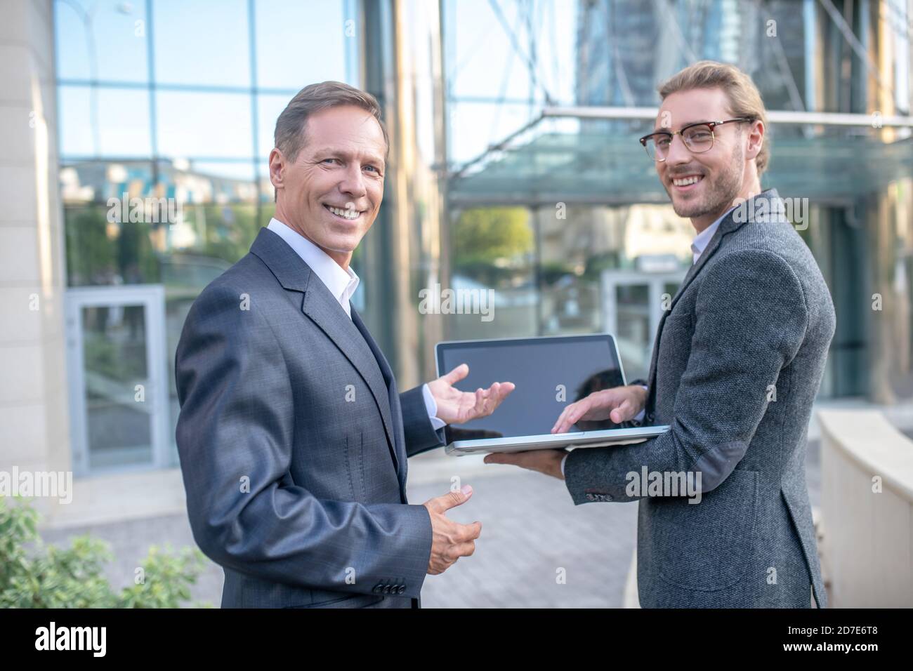Two male business partners checking laptop, discussing project outside ...