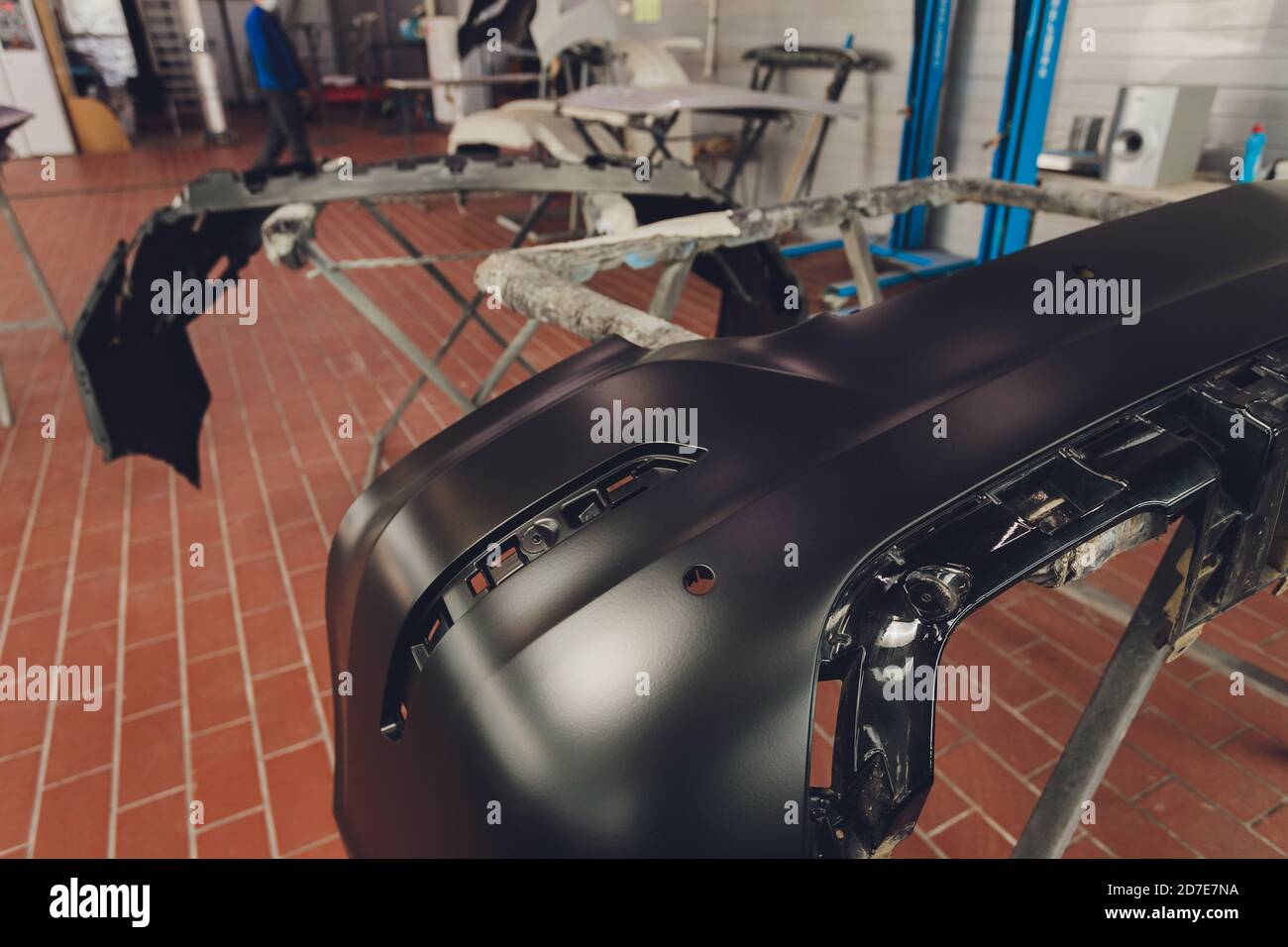 Auto bumper part is installed on the racks after painting in car repair ...