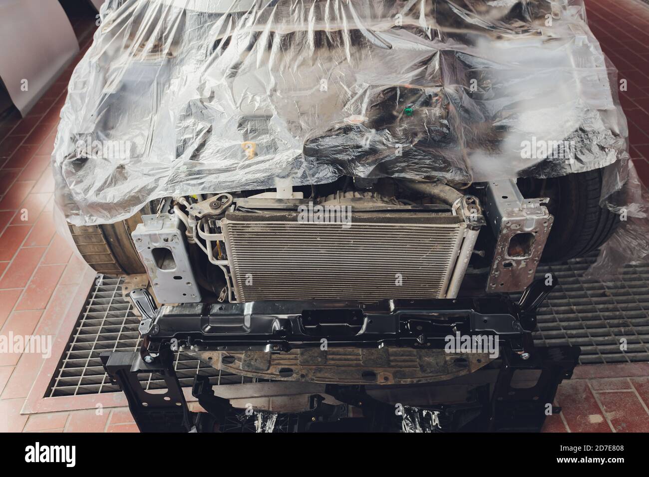 A broken car color silver, wrapped in a plastic coating. The car is ...