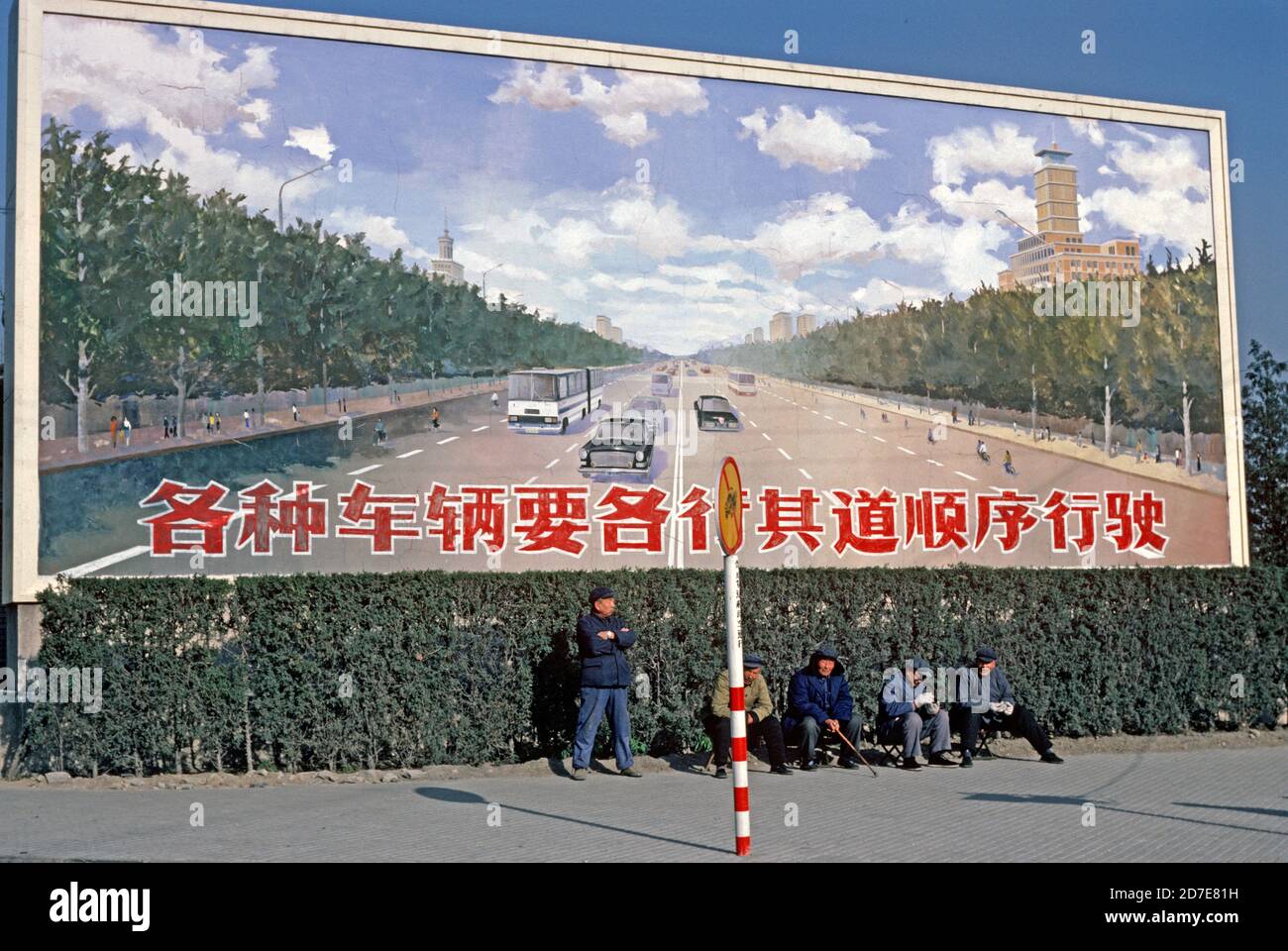 Chinese standing and sitting infront of road traffic poster, Beijing ...
