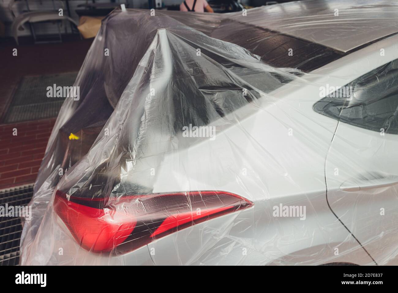 A broken car color silver, wrapped in a plastic coating. The car is ...