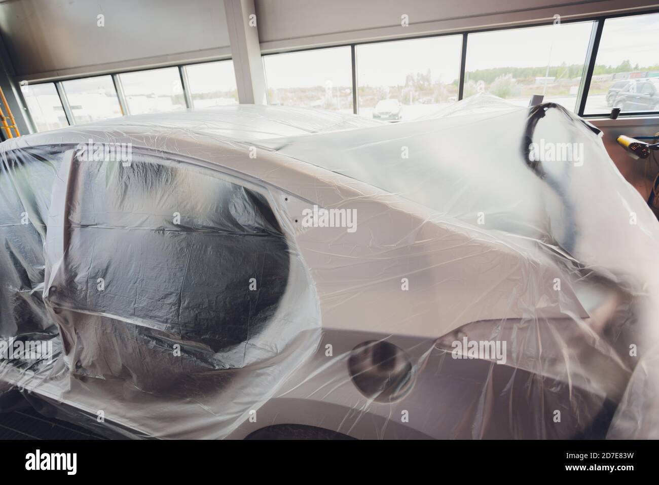 A broken car color silver, wrapped in a plastic coating. The car is ...