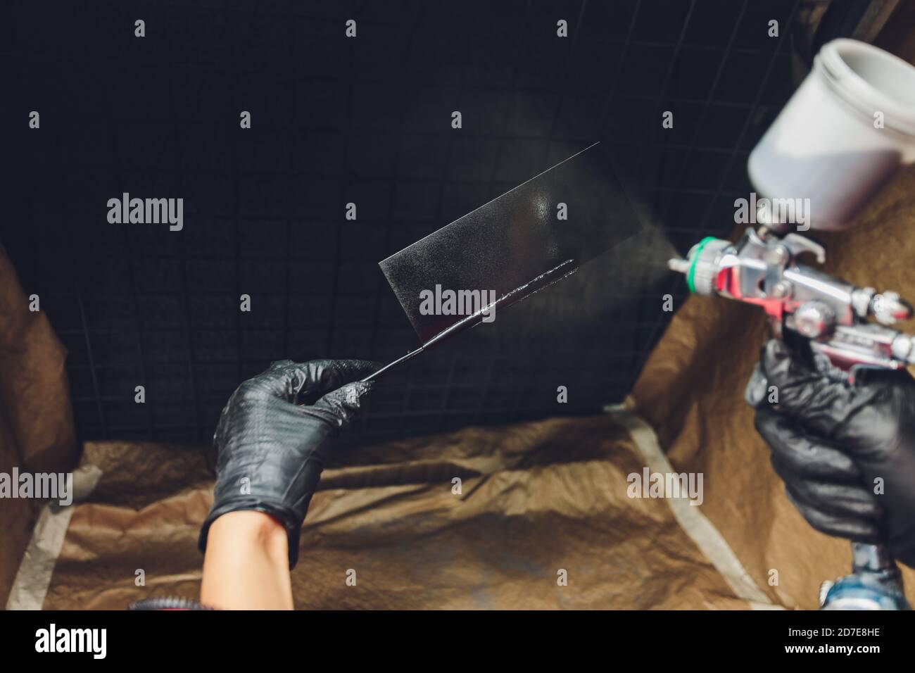 A spray gun in the master s hands is aimed at a test plate and sprays ...