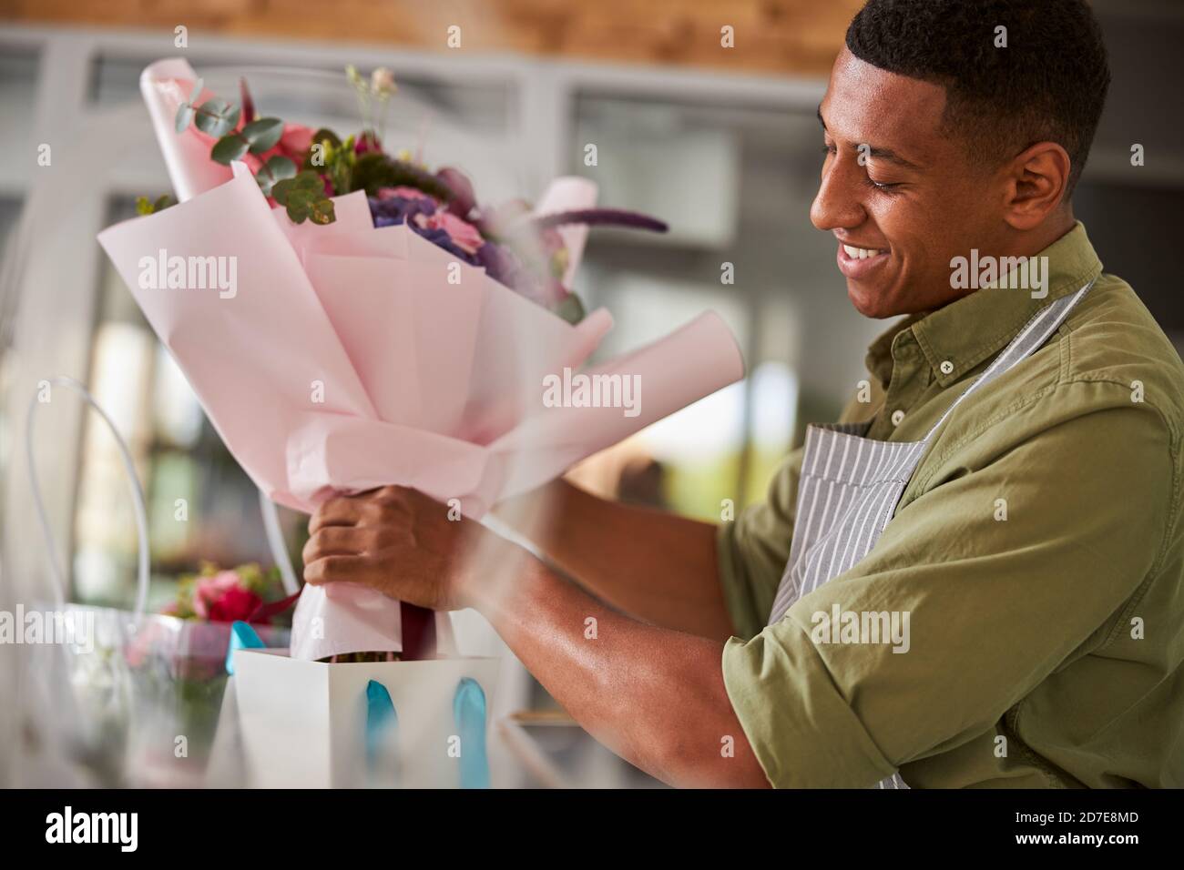 Pleasant floral artist packing a bouquet in a small bag Stock Photo - Alamy