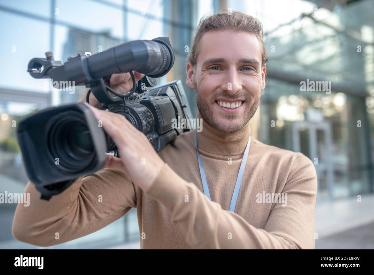 Smiling cameraman holding camera on his shoulder outside Stock Photo ...