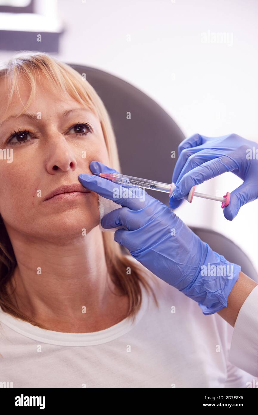 Mature Woman Sitting In Chair Being Give Botox Injection By Female ...