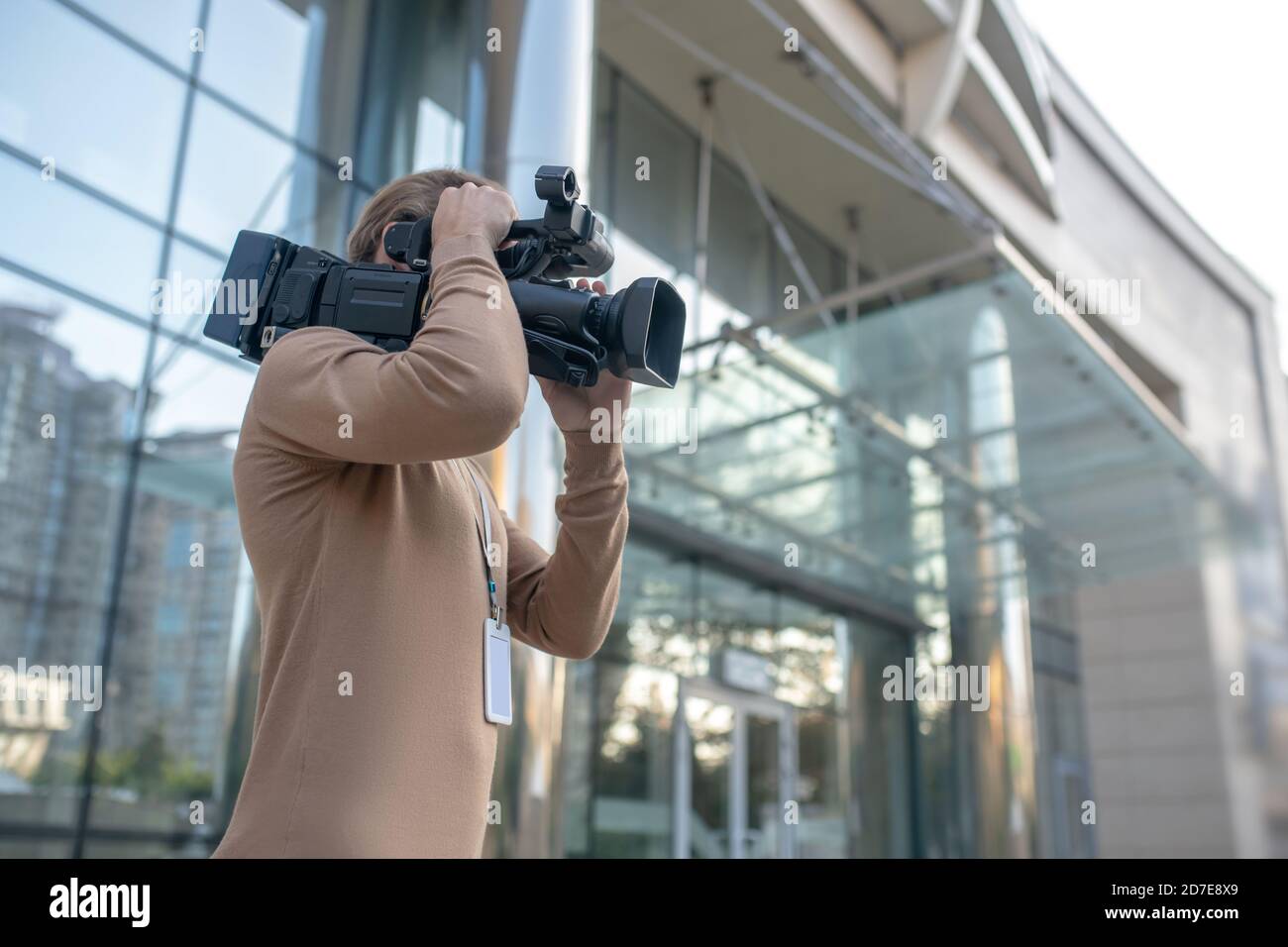 Cameraman walking outside with camera on his shoulder Stock Photo - Alamy