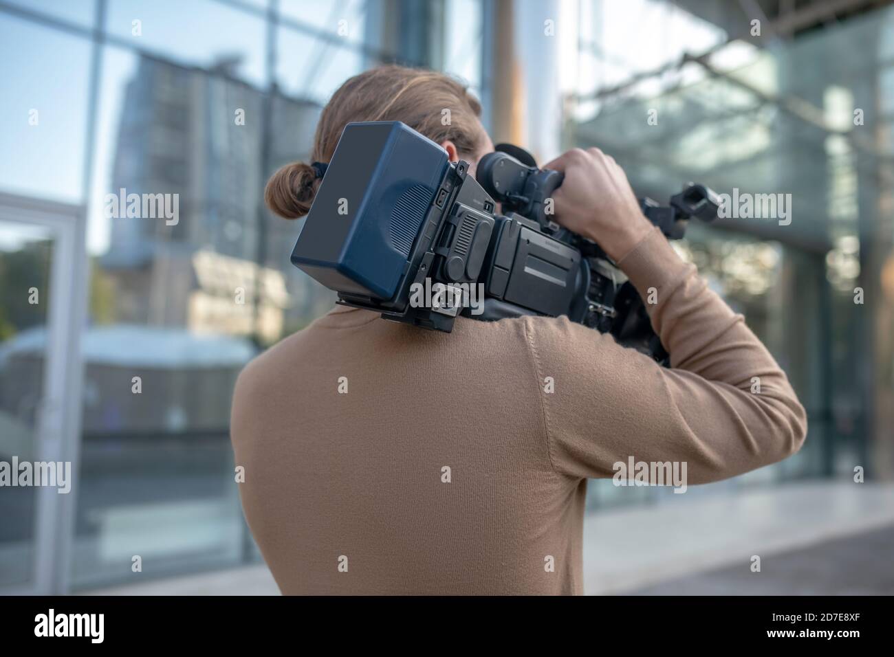 Rear view of cameraman carrying camera on his shoulder Stock Photo - Alamy