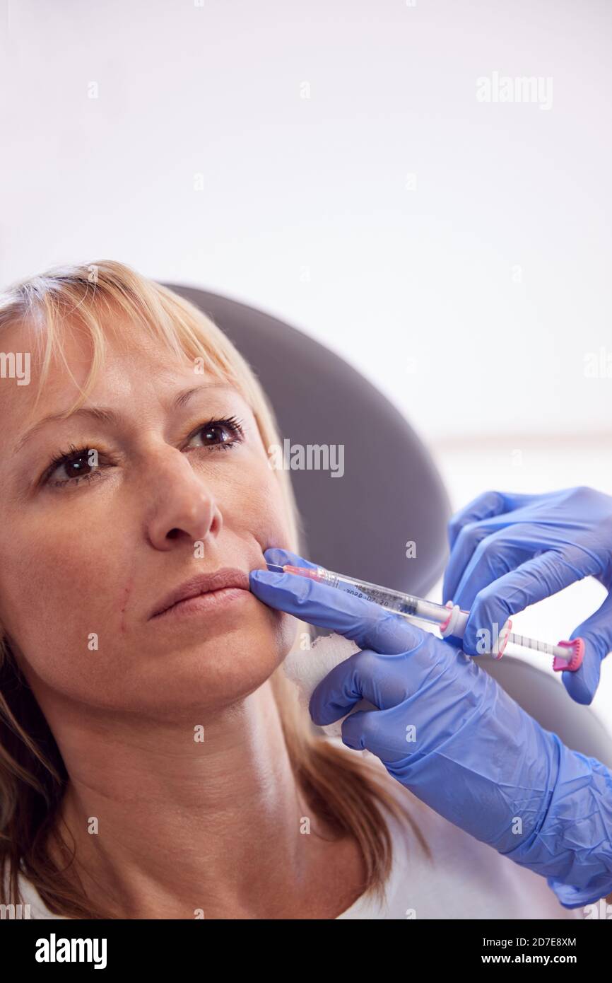 Mature Woman Sitting In Chair Being Give Botox Injection By Female ...