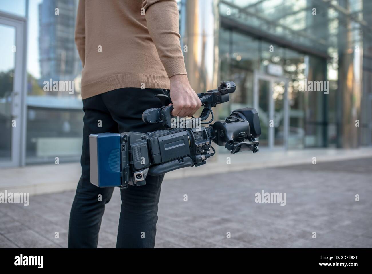Cameraman holding camera in his right hand outside Stock Photo - Alamy