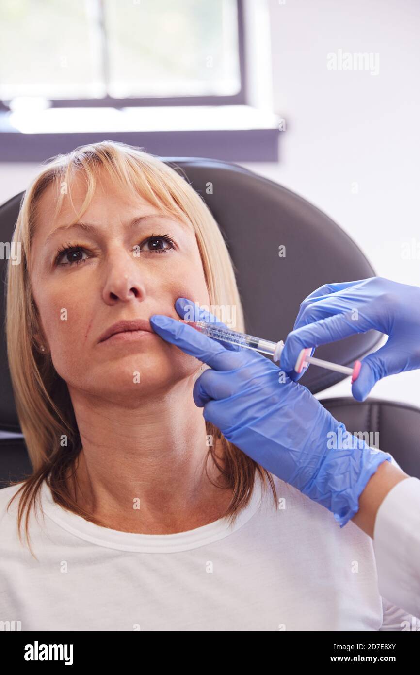 Mature Woman Sitting In Chair Being Give Botox Injection By Female ...