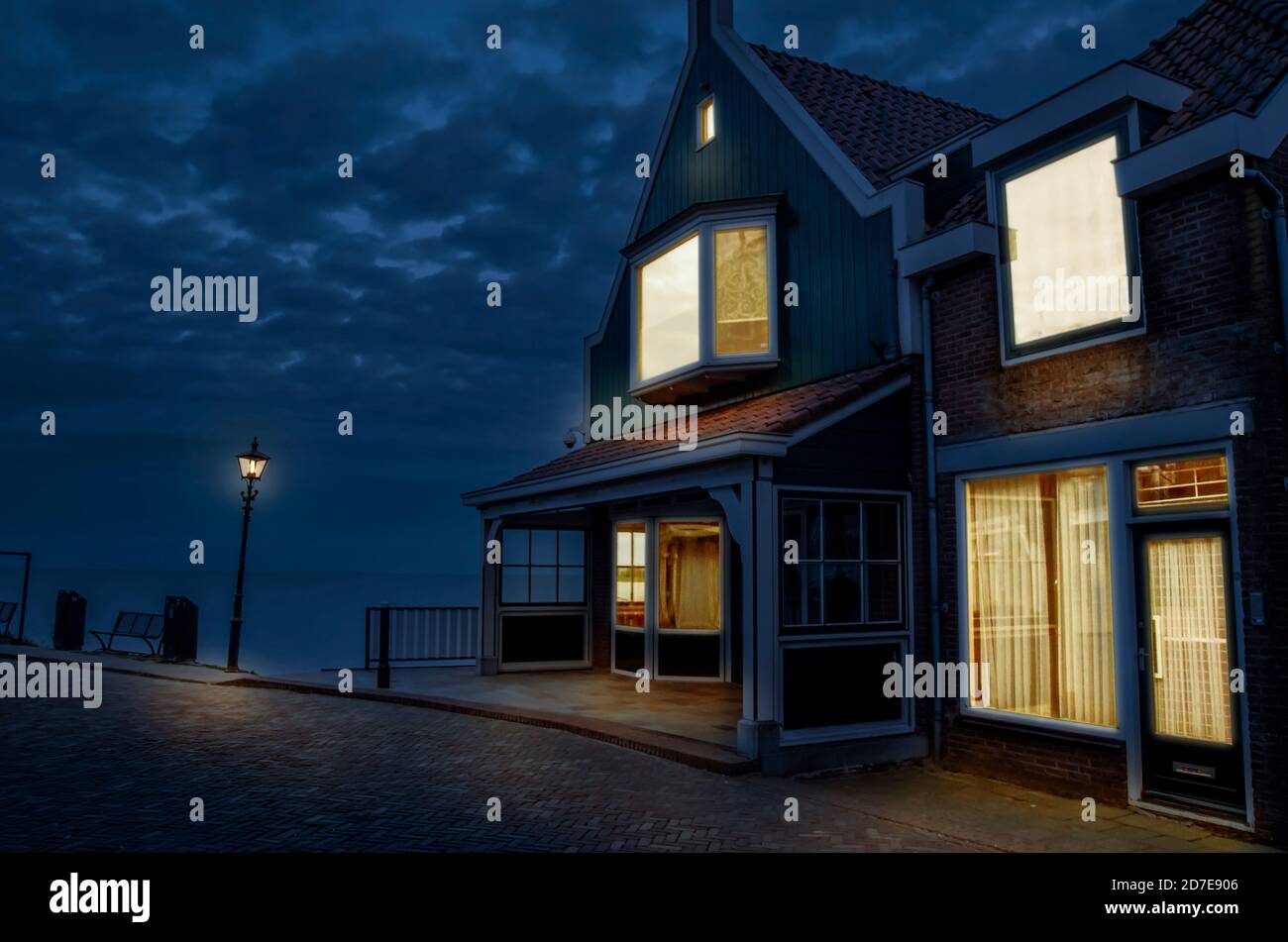 Wooden house illuminated at night with view of beautiful lake or sea ...