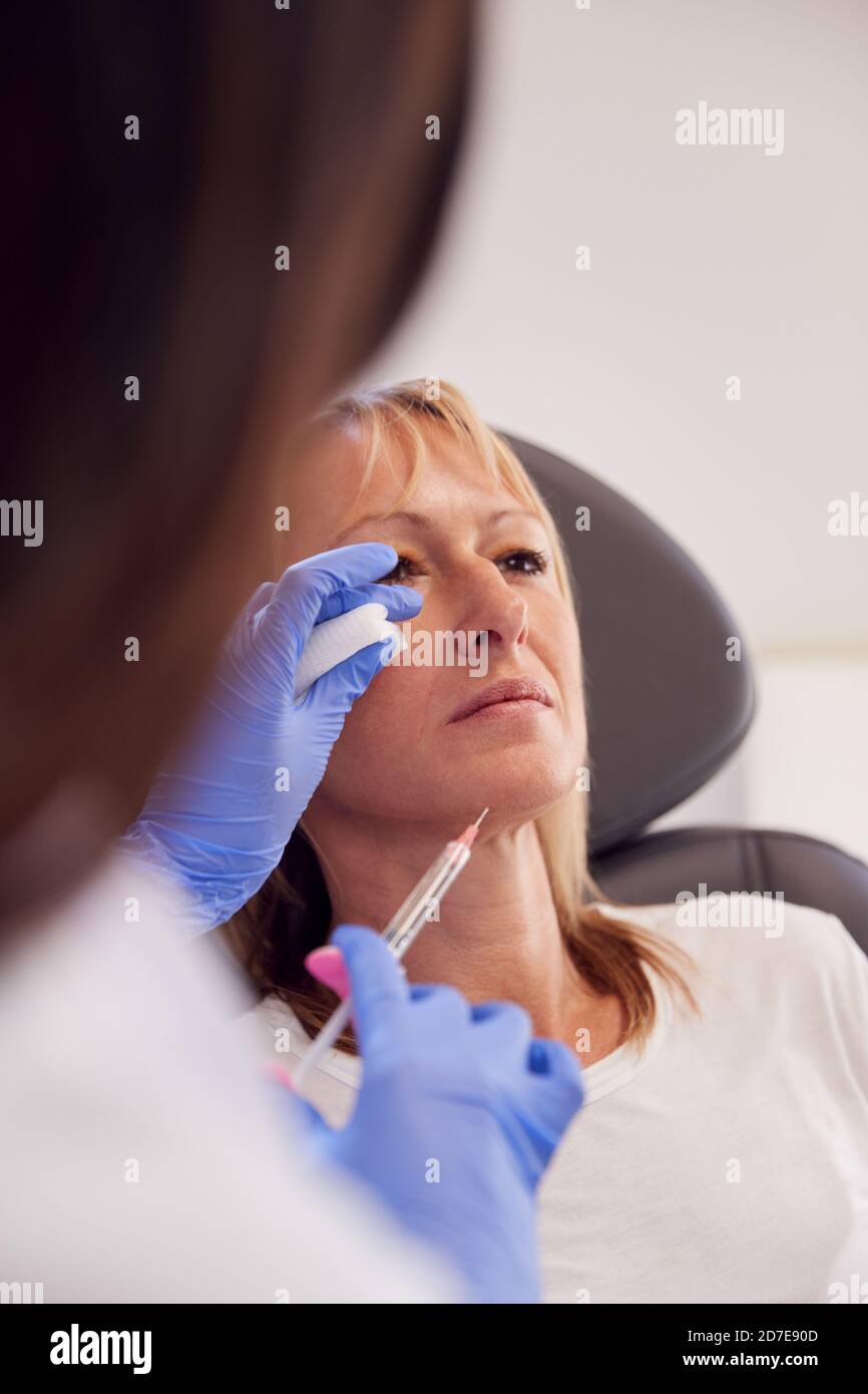 Mature Woman Sitting In Chair Being Give Botox Injection By Female ...