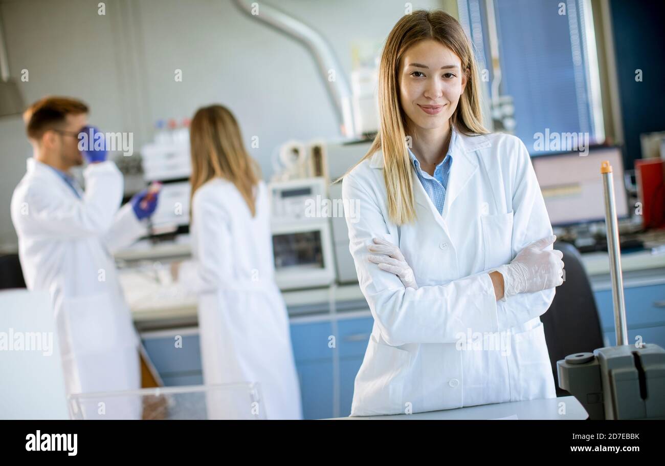 Young female scientist in white lab coat standing in the biomedical lab ...