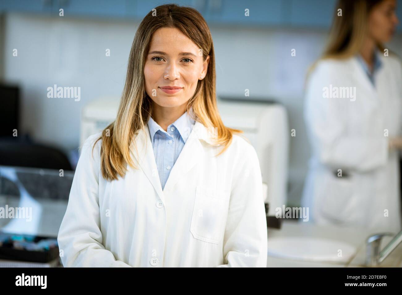 Young female scientist in white lab coat standing in the biomedical lab ...