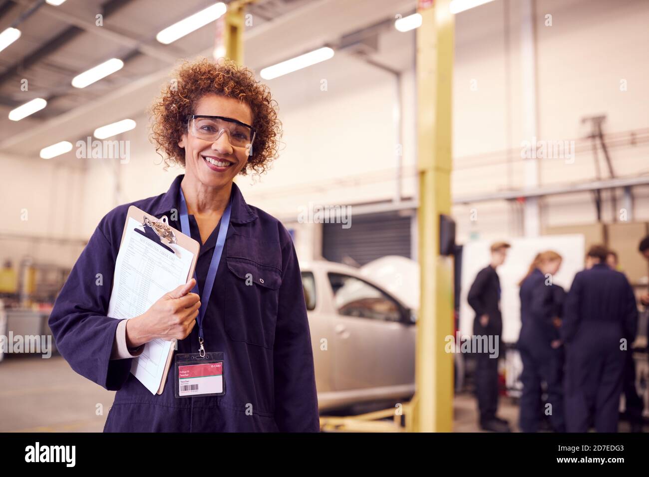 Portrait Of Female Tutor With Safety Glasses Teaching Auto Mechanic ...