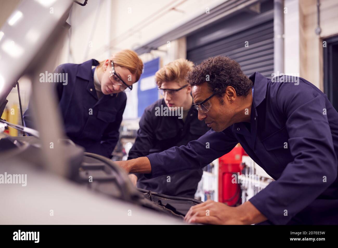 Male Tutor With Students Looking At Car Engine On Auto Mechanic ...