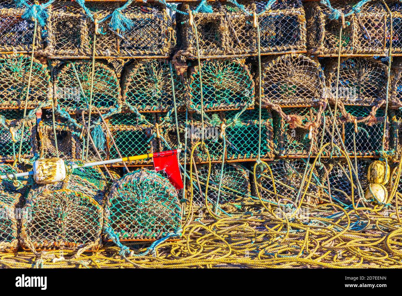 Lobster pots, ropes and marker flags piled on the harbourside at ...