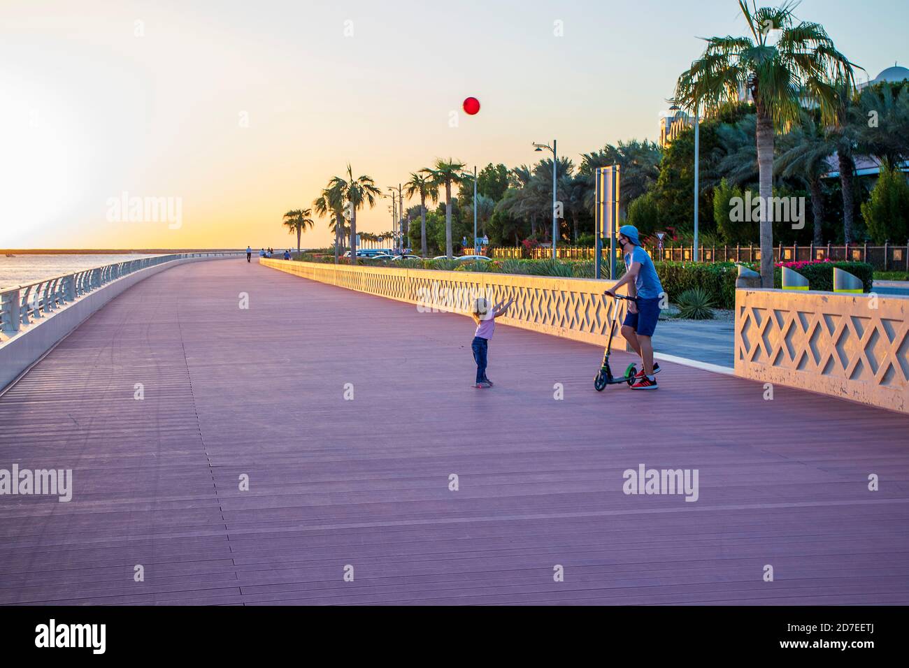 Children playing with balloon on boardwalk during sunset hour. Outdoors ...