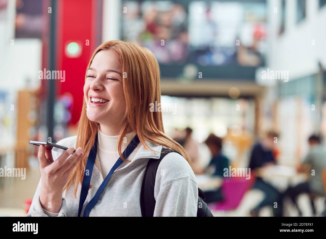 Smiling Female College Student Talking Into Mobile Phone In Busy ...