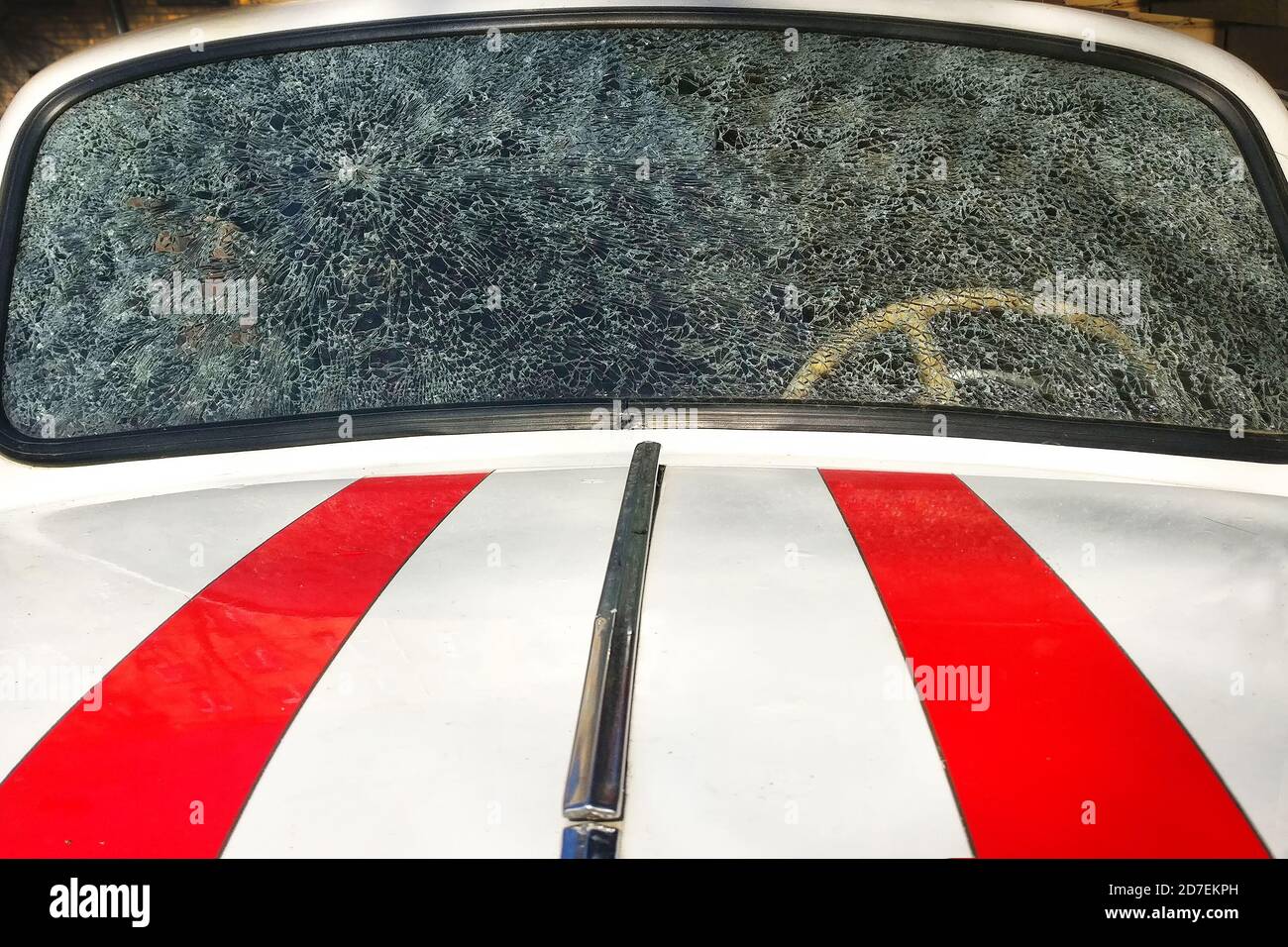 Damaged retro white car with red stripes on the hood. Broken windshield ...