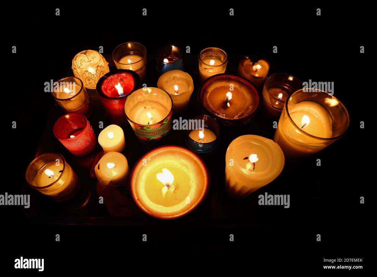 Many candles of different sizes and styles in the dark Stock Photo - Alamy