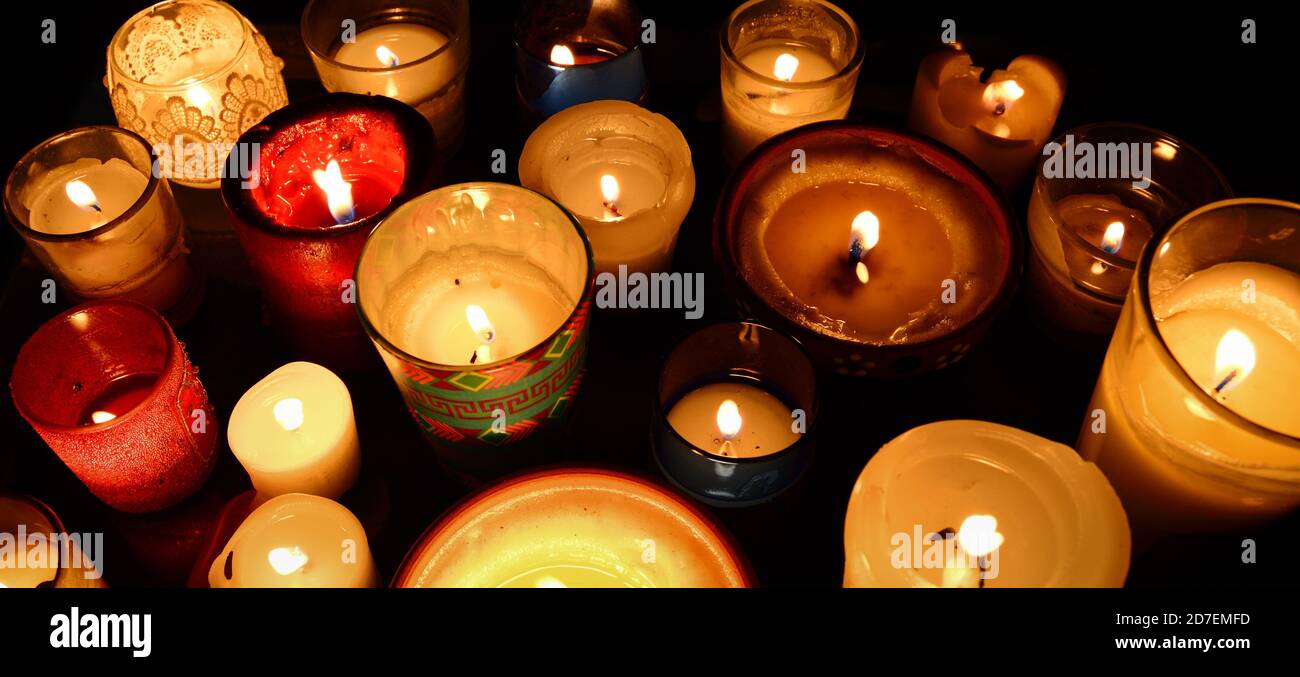 Many candles of different sizes and styles in the dark Stock Photo - Alamy