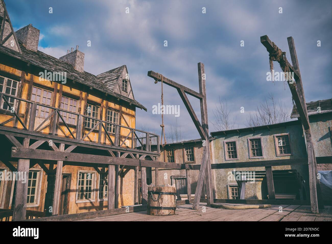 Old wooden houses and the gallows with the rope on the square retro ...
