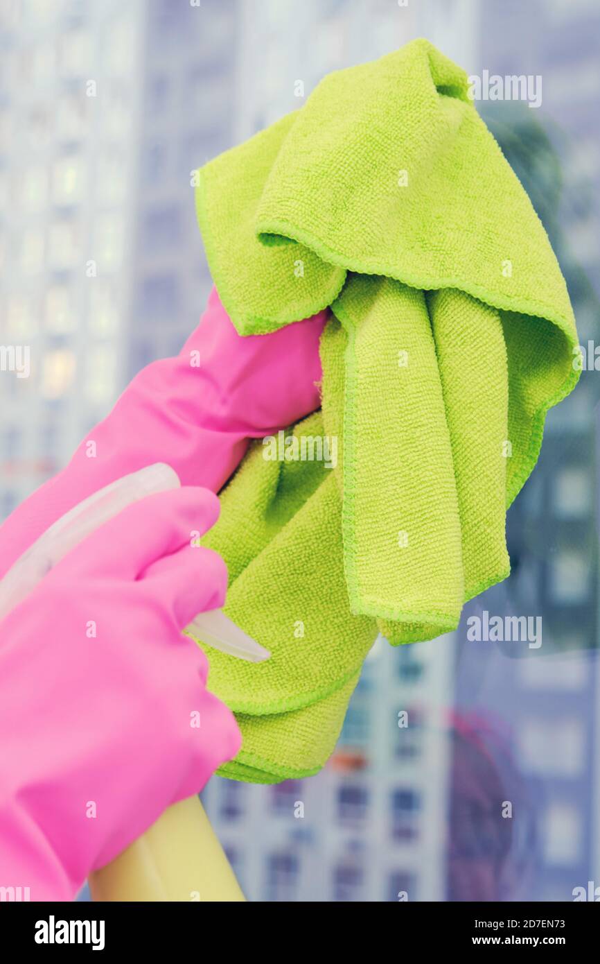 Gloved hands wash the window with a green cloth and the spray gun ...