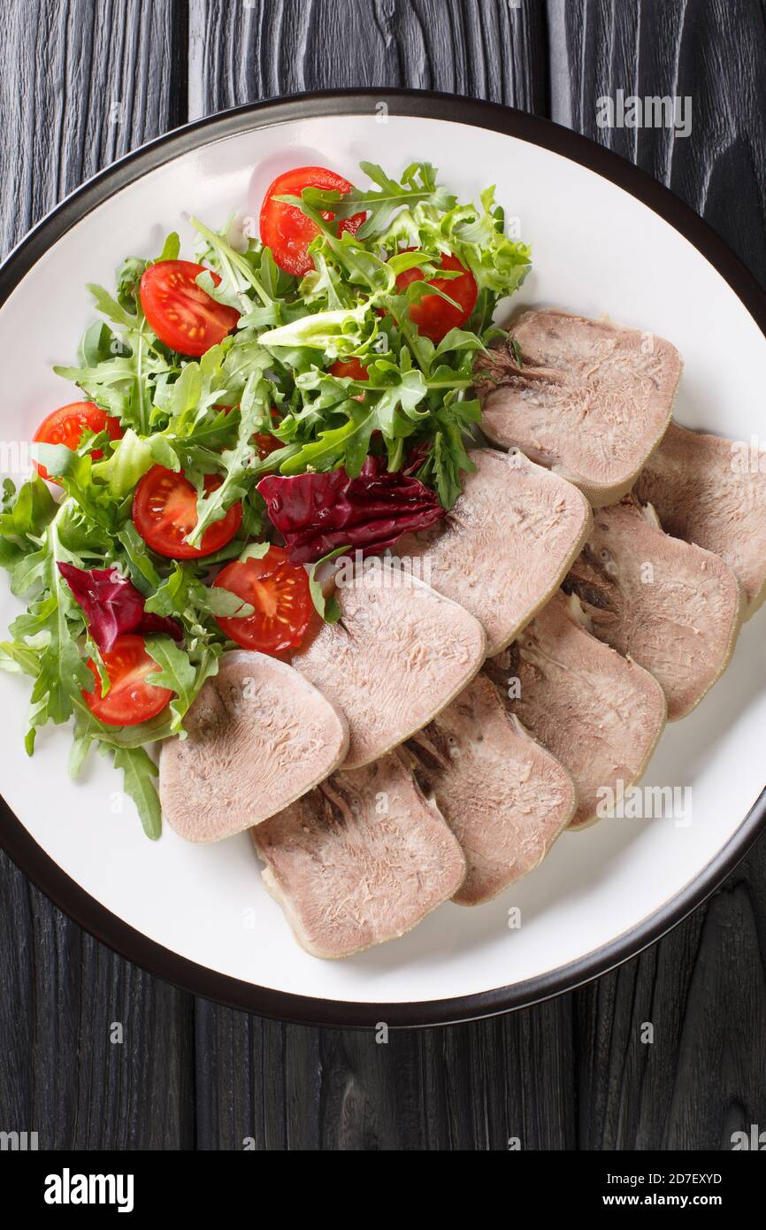 Cold cuts of beef tongue served with fresh salad closeup at plate on ...