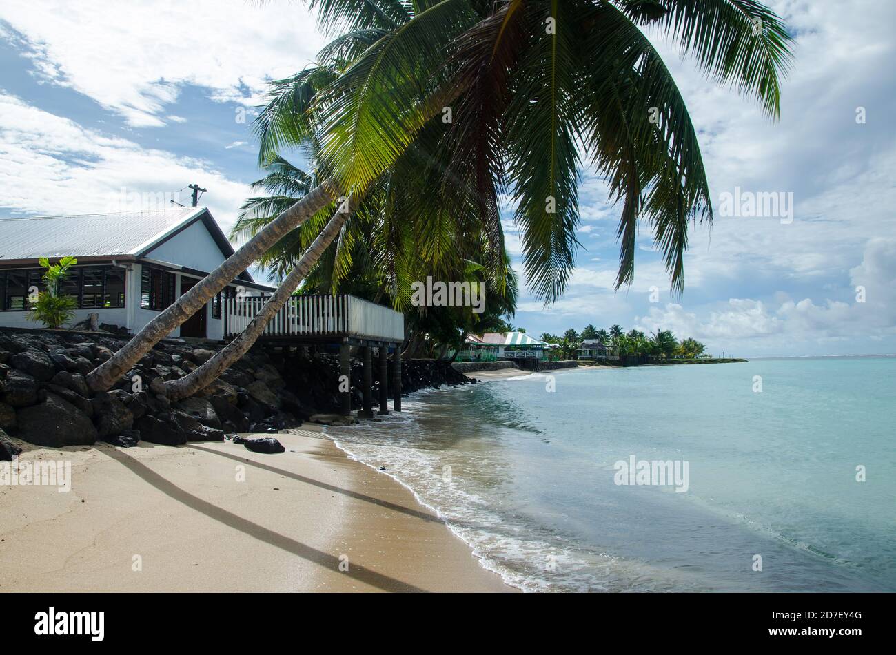 Cottages on the beach surrounded by greenery and sea under a cloudy sky ...