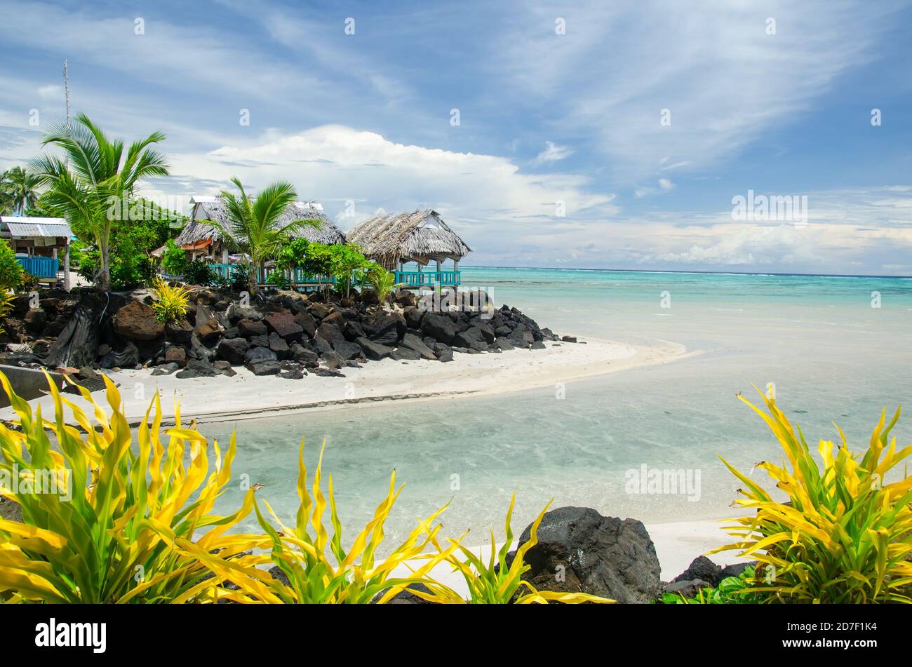 Beach surrounded by palm trees, small cottages, and the sea in the ...