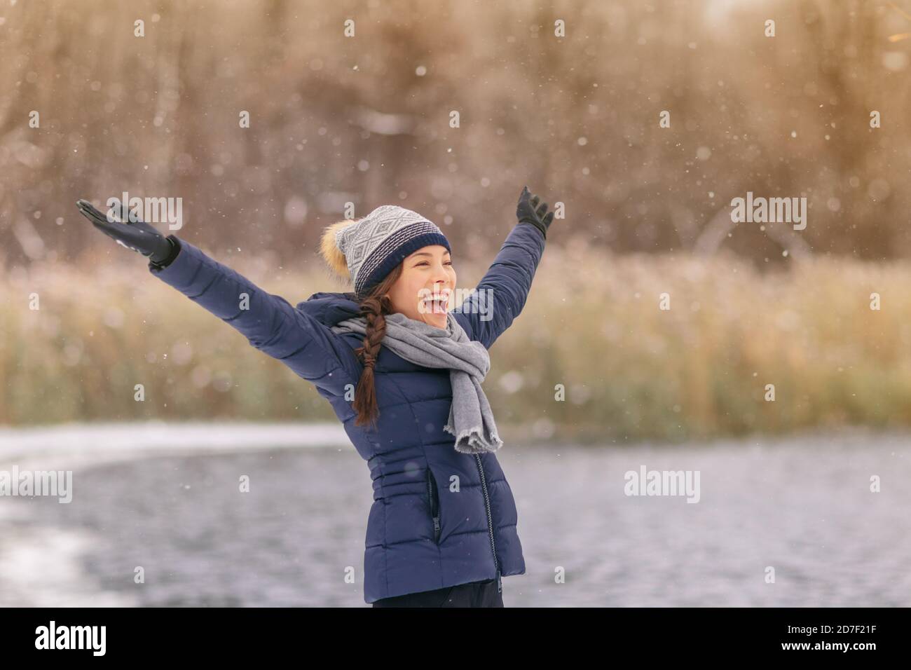 Happy winter snow fun Asian woman playing outside in snowfall enjoying ...