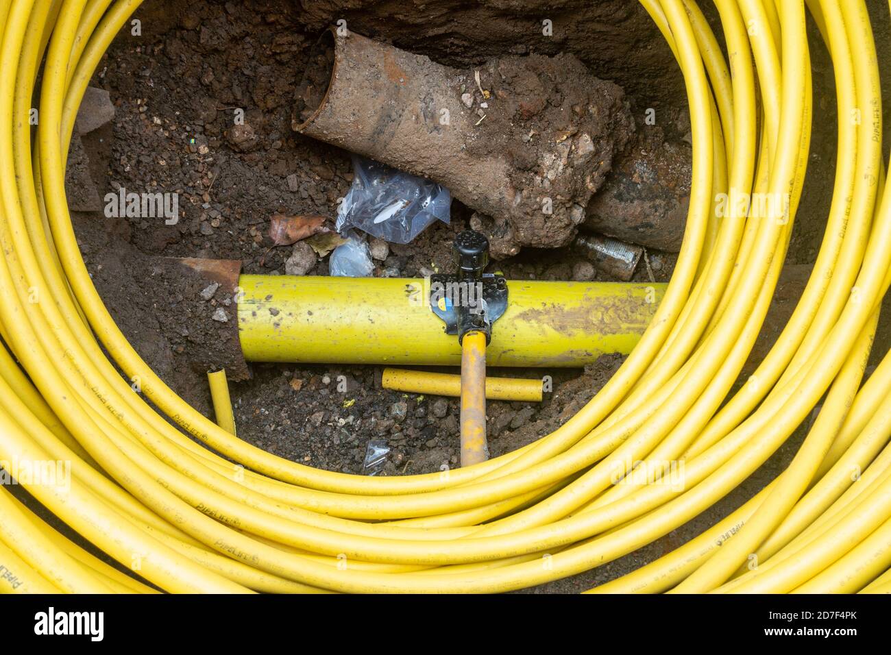 A large hole in the ground as a yellow mains water pipe is being ...