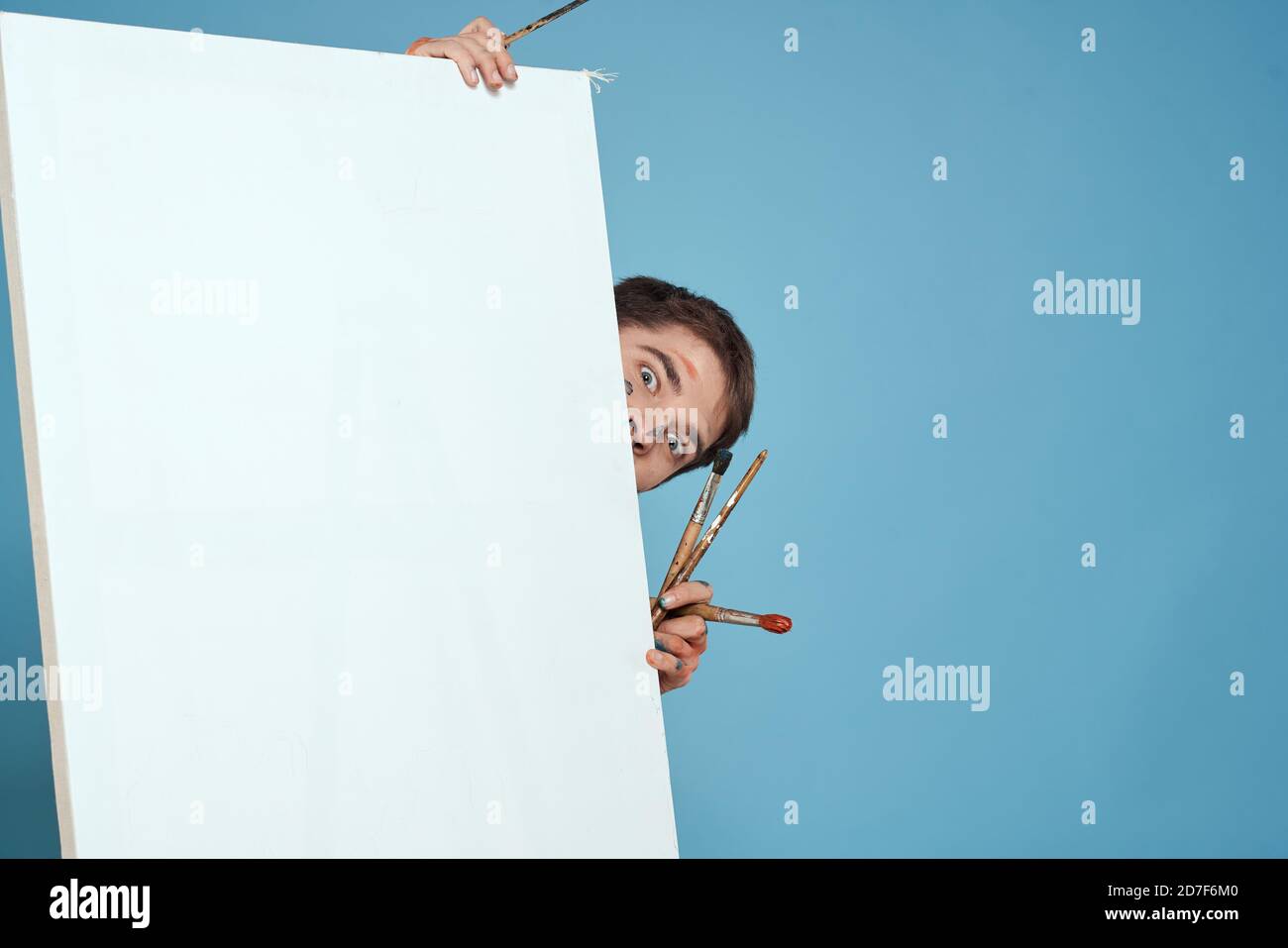 Male artist backs up behind easel brush art creativity blue background ...