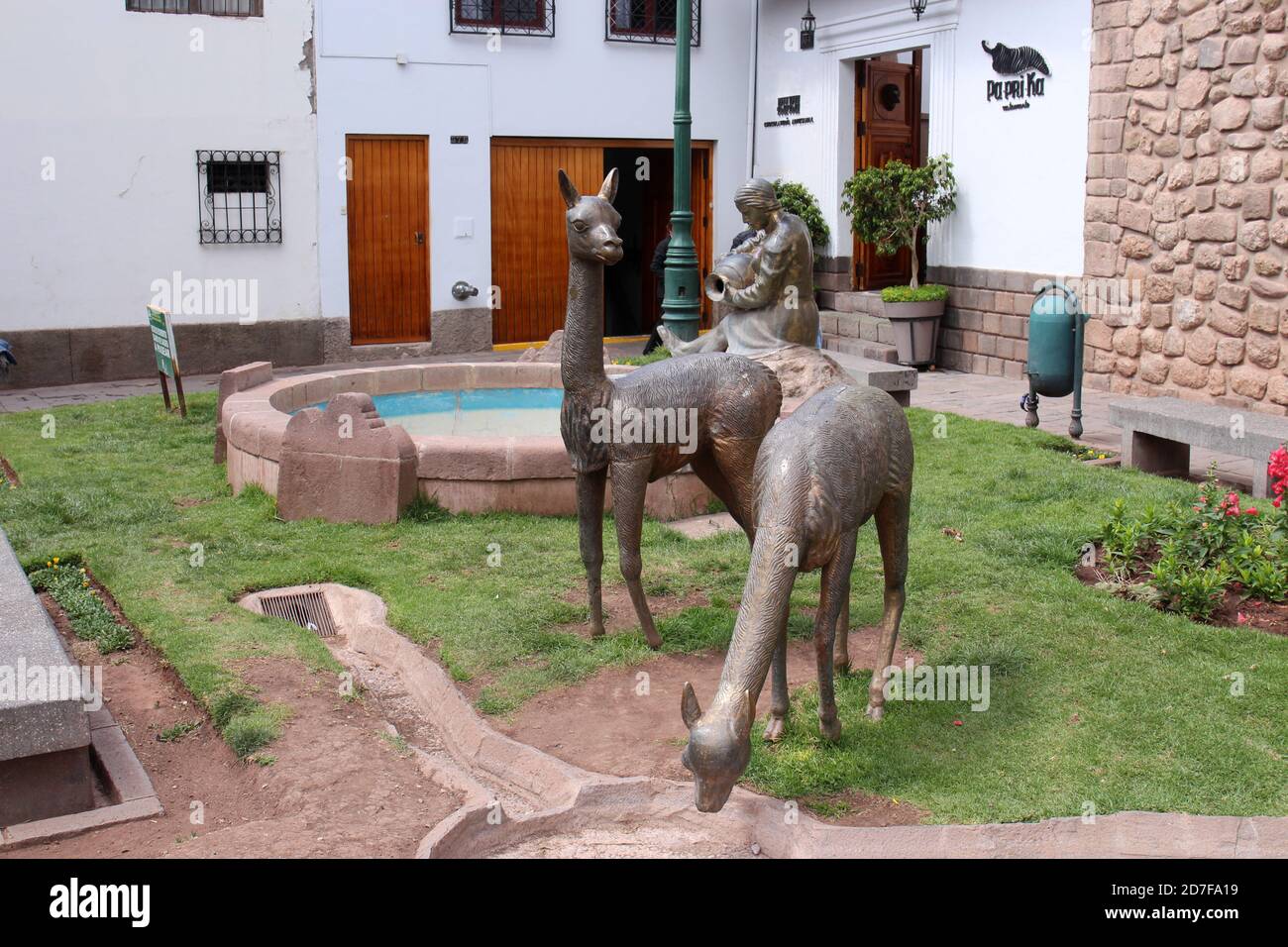 A statue of a women pouring water into a fountain with two llamas ...