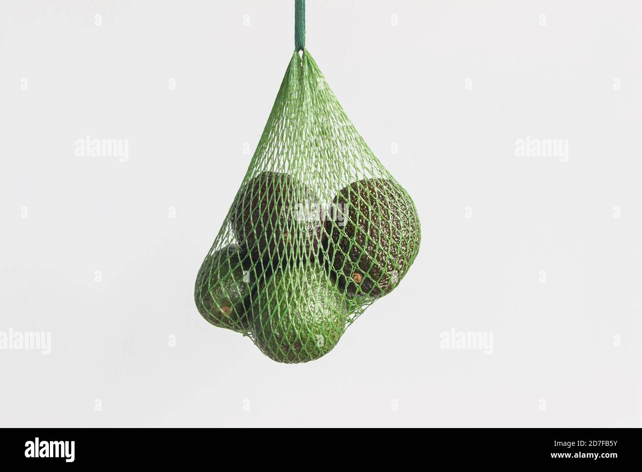 organic avocado in green mesh bag on white background Stock Photo - Alamy