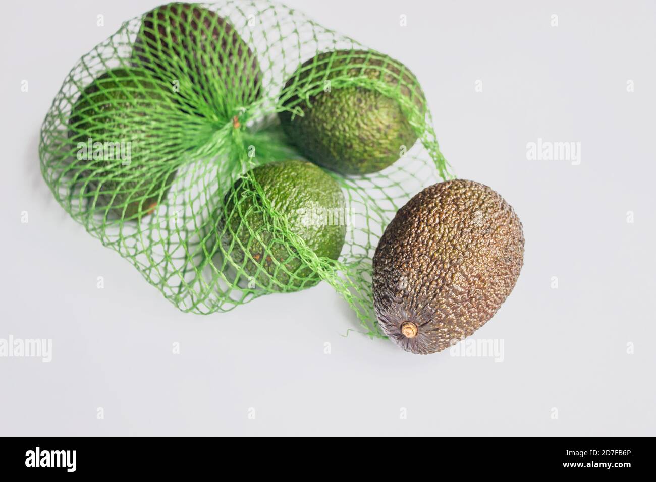 organic avocado in green mesh bag on white background Stock Photo - Alamy