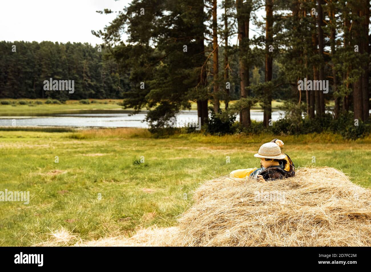 little boy in a hat lying on a haystack in the field. Autumn ...