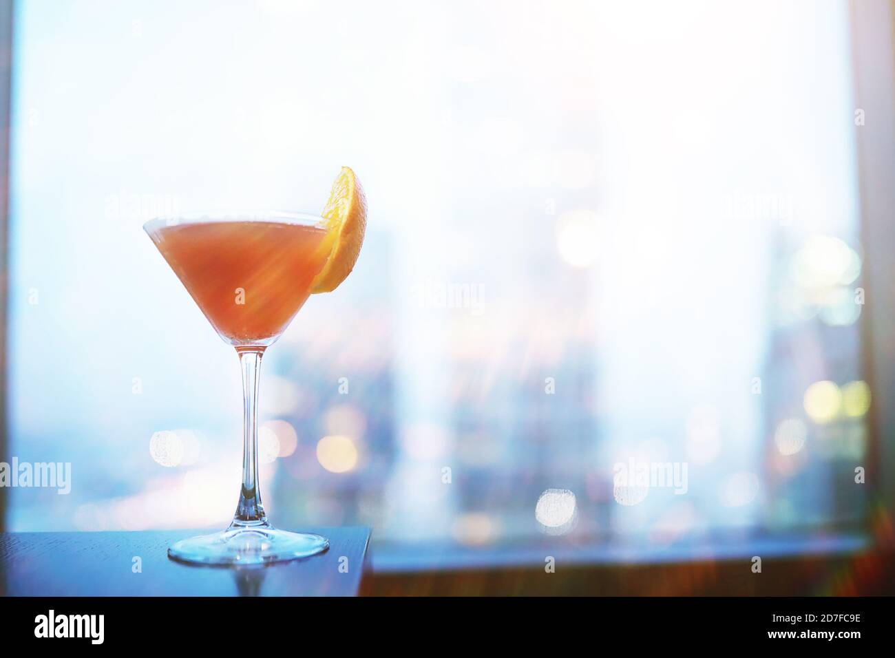 Cocktail glasses on the windowsill by the glass of a tall building ...