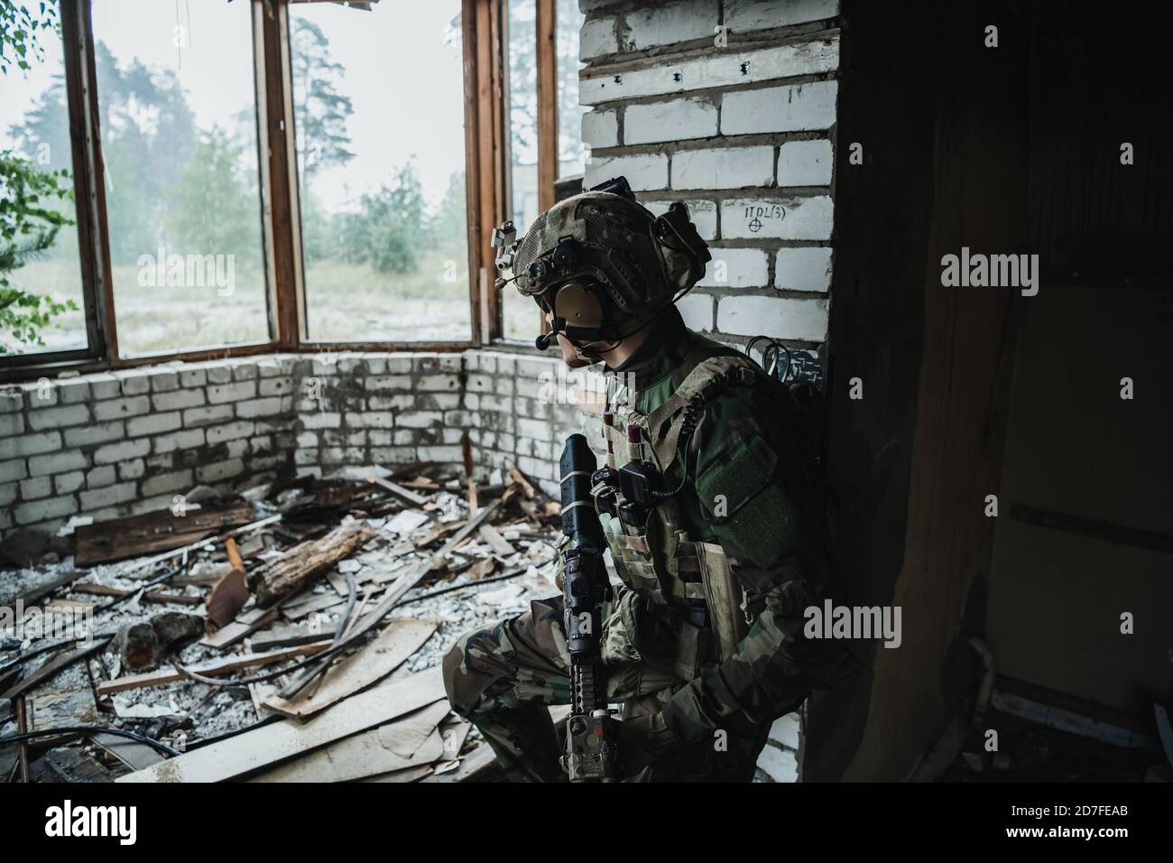 Military man with assault rifle standing inside building, he is ready ...