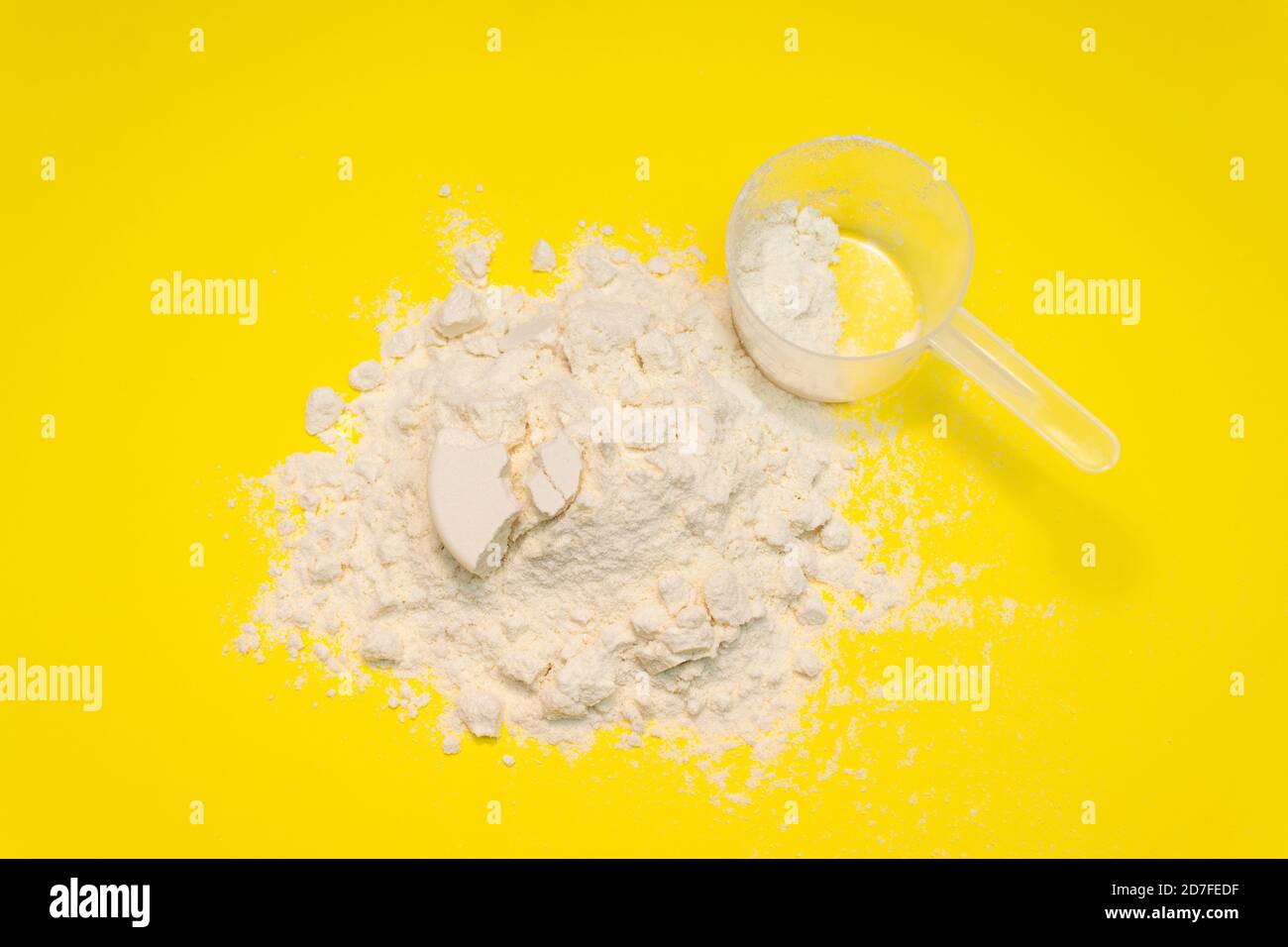 Measuring cup from a white powder whey protein on a yellow background ...