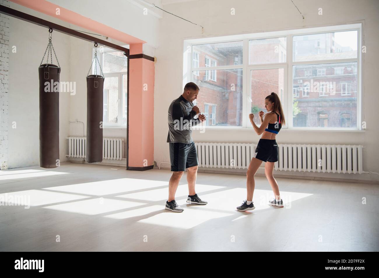 An attractive young boxer teaches his girlfriend boxing techniques in a ...