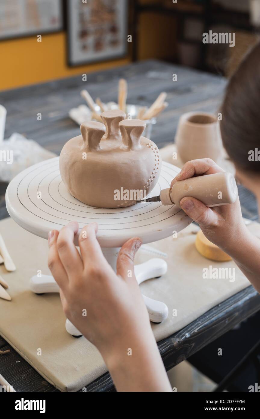 Child in the process of decorating the clay vase. Children pottery ...